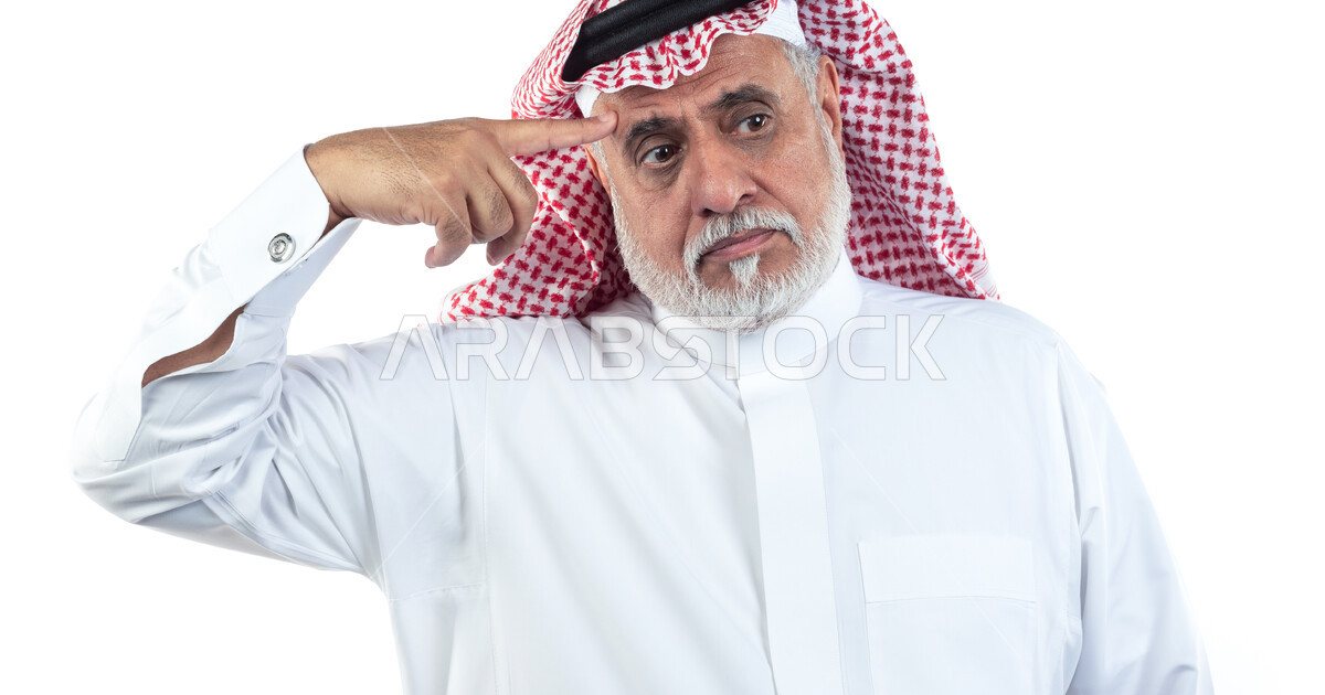 Portrait of an old Saudi Arab man pointing his finger at his head with ...