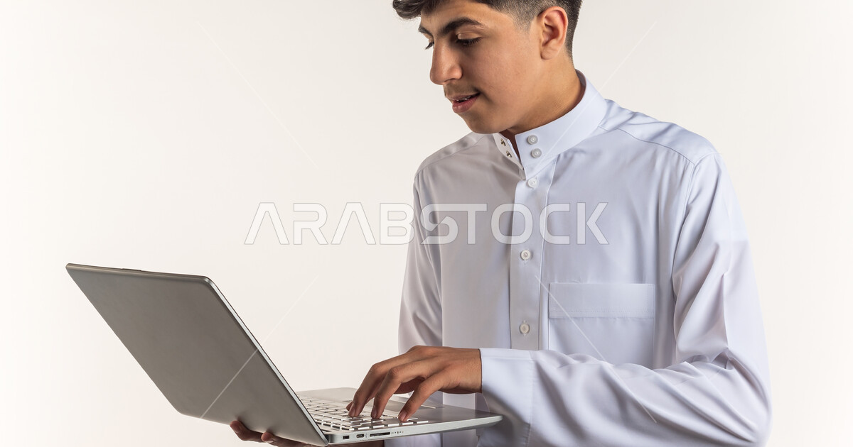 Portrait of a young Saudi Arabian Gulf teenager using a laptop ...