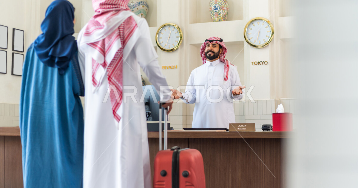 A Saudi tourist couple making reservations at the hotel reception ...