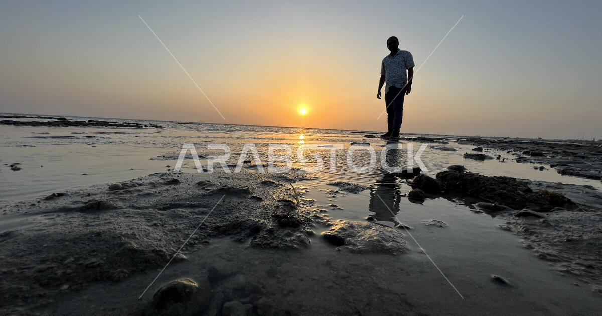 Sunset on Al Seef Beach, enjoying the scenery, silhouette of a young ...