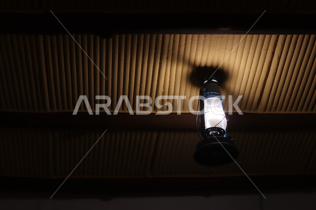 A small, luminous lantern hanging on the wooden ceiling, dim lighting ...