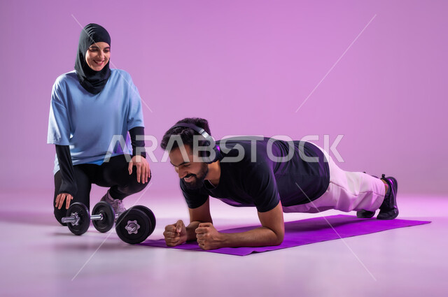 Doing push-ups, a portrait of a veiled Saudi Gulf Arab trainer wearing ...