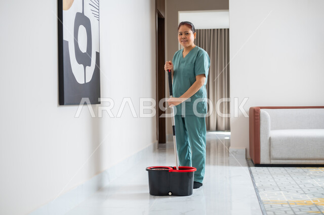 Taking care of cleaning and doing routine tasks, a cleaning lady looks ...