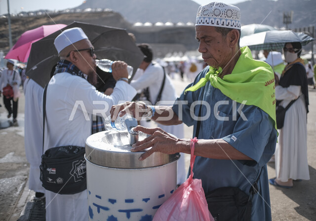 Hajj season in Saudi Arabia, close-up of a pilgrim filling water from a ...