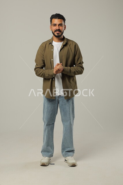 Portrait of a handsome young Arab Gulf Saudi man in casual wear closing ...
