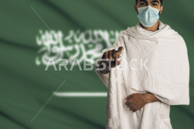 A Saudi Arabian Gulf Muslim man in Ihram and wearing a mask, following ...