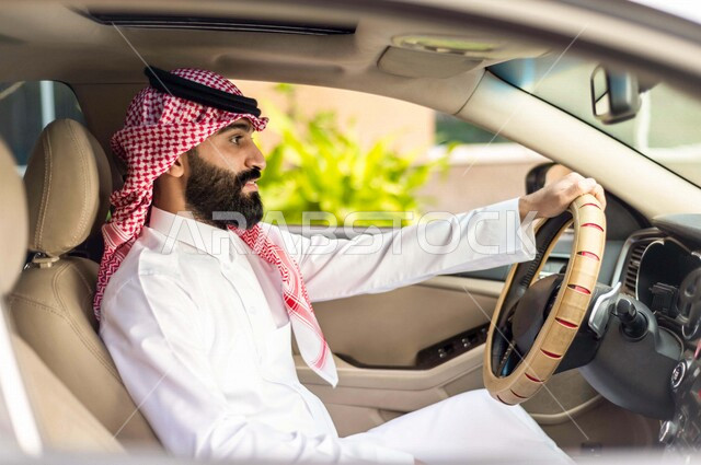 A Saudi Arabian Gulf man wearing the Saudi traditional dress, driving ...