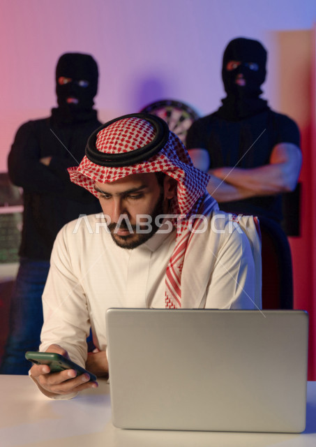 A Saudi Arabian Gulf man using a mobile phone, sitting in front of a ...