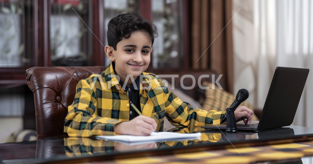 A student sitting at the study table, holding a pen in his hand and ...