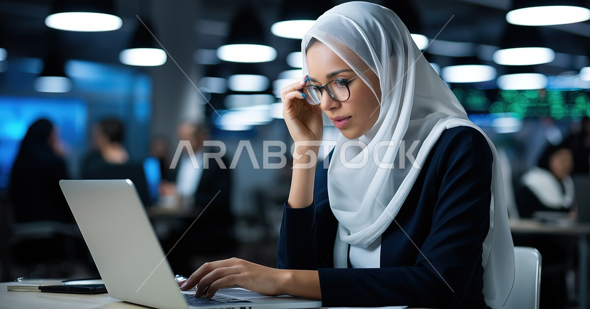 A veiled Saudi Gulf Arab woman immersed in work, communicating with ...