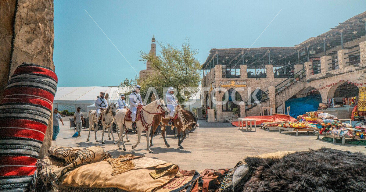 Traditional traditional costumes, Qatari Gulf Arab men riding purebred Arabian horses in Souq ...
