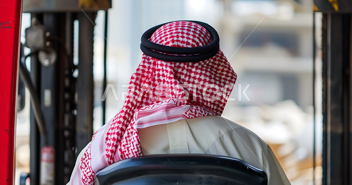 Working on a forklift, back view of a Saudi Arabian Gulf man wearing ...