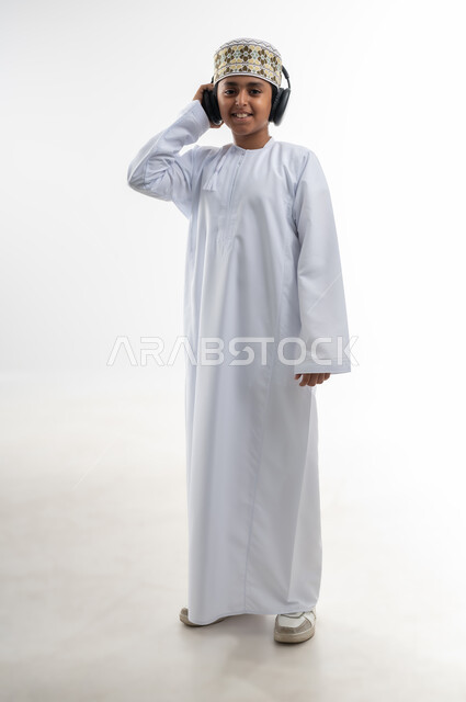 Portrait of a young Arab Gulf Omani man wearing a dishdasha and a ...