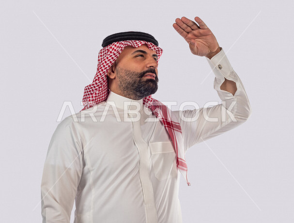 Portrait of a Gulf Saudi man raising his hand looking in focus at ...