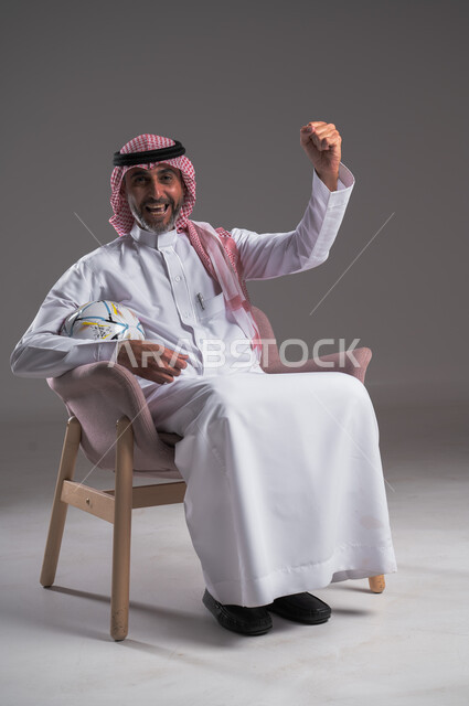 Watching and following a football match, portrait of a smiling Saudi ...
