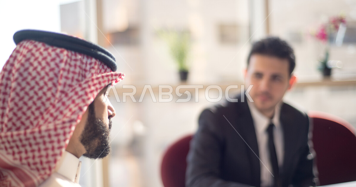 Arab Gulf Saudi businessmen sitting at the desk, discussing work ...