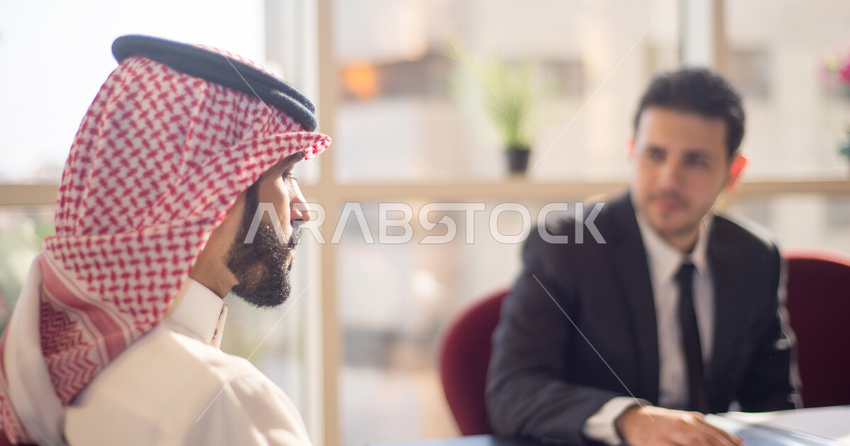 Arab Gulf Saudi businessmen sitting at the desk, discussing work ...