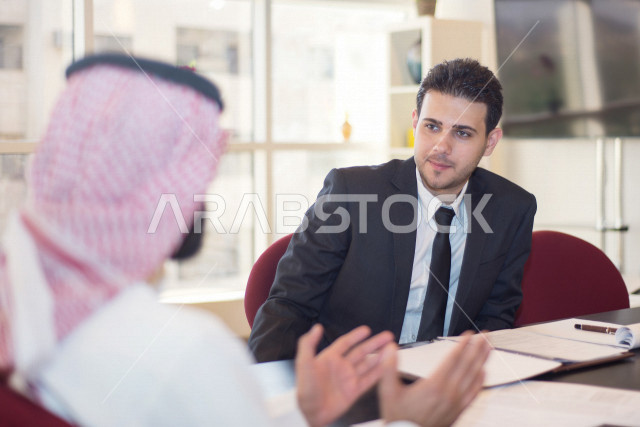 Arab Gulf Saudi businessmen sitting at the desk, discussing work ...