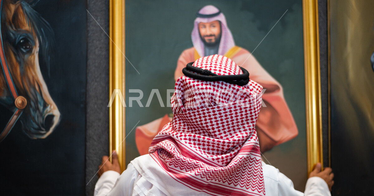 A picture from the back of a talented Saudi artist holding in his hand ...