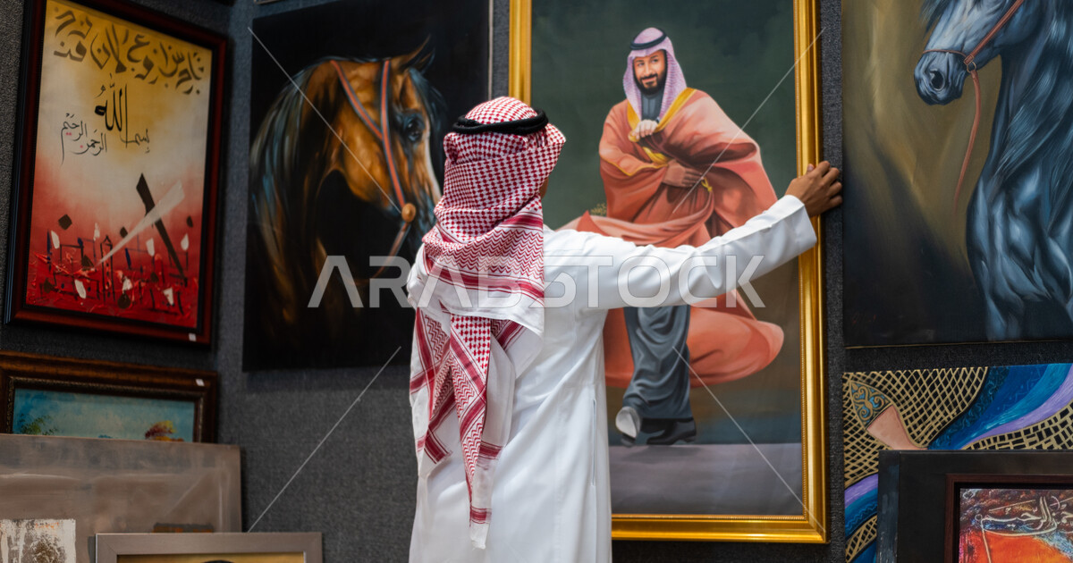 A talented Saudi Arabian Gulf artist holds in his hand a painting with ...