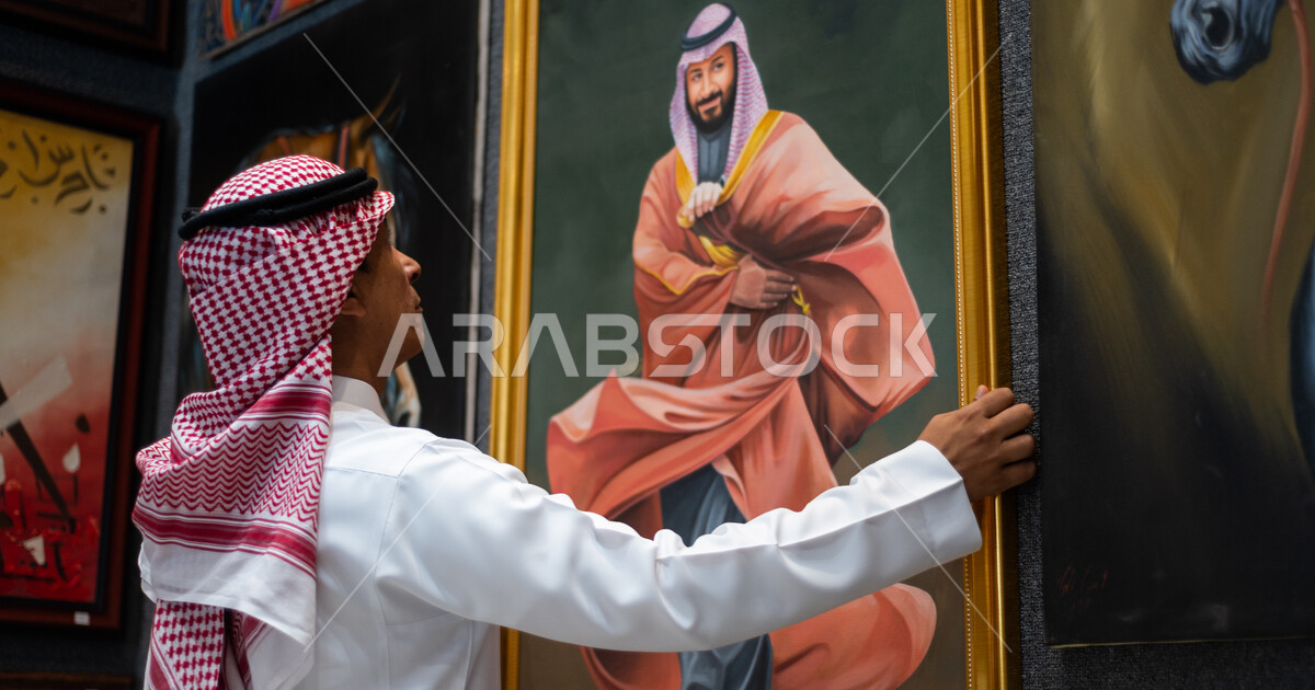 A talented Saudi Arabian Gulf artist holds in his hand a painting with ...