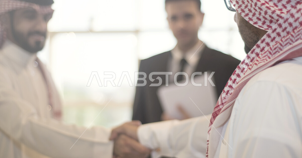 Saudi Arabian Gulf business team Two Saudi Arab men shake hands after ...