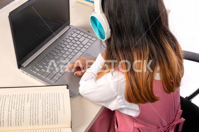 A Saudi Arabian Gulf schoolgirl wearing a school uniform and a headset ...