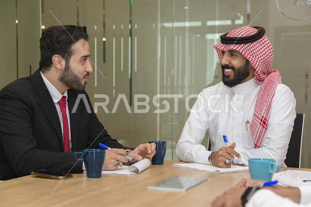 رجل أعمال خليجي سعودي بإجتماع إداري مع رجل عربي ببدلة يتناقشون في غرفة