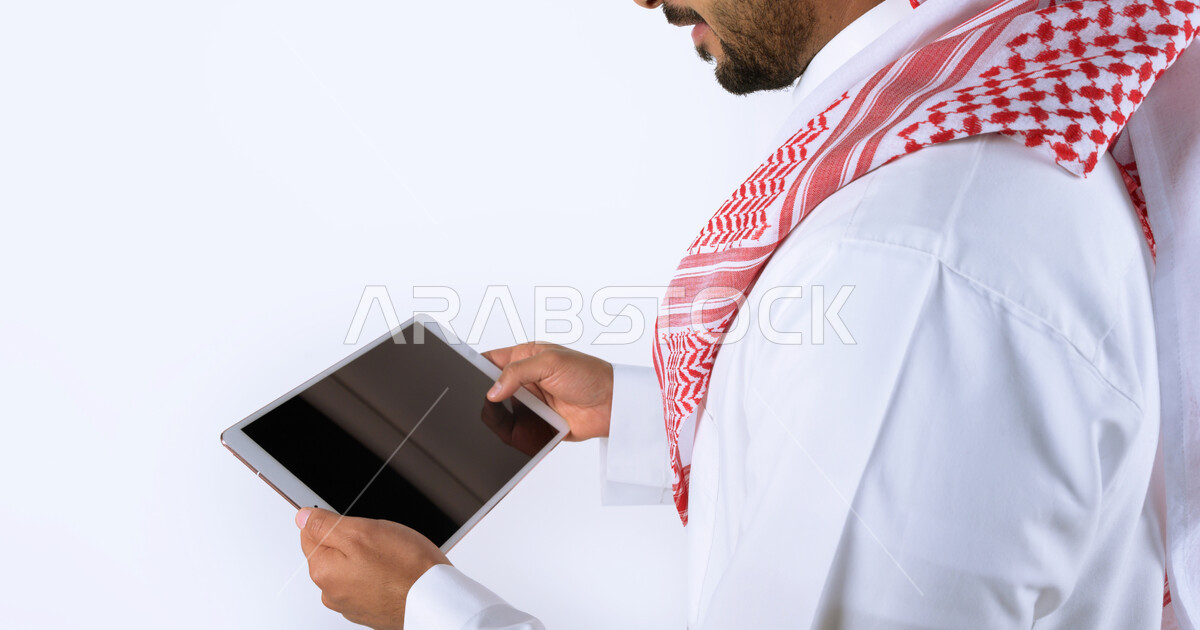 Portrait of a Saudi Arabian Gulf man holding a tablet device in his ...