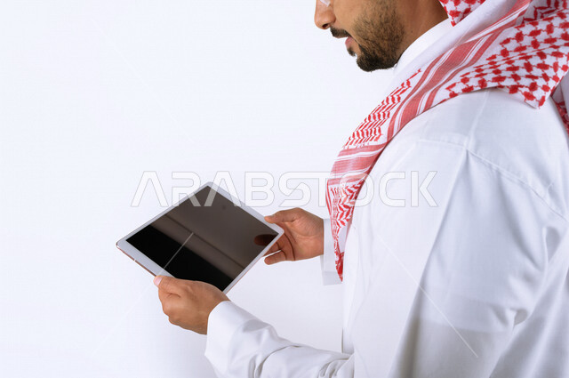 Portrait of a Saudi Arabian Gulf man holding a tablet device in his ...