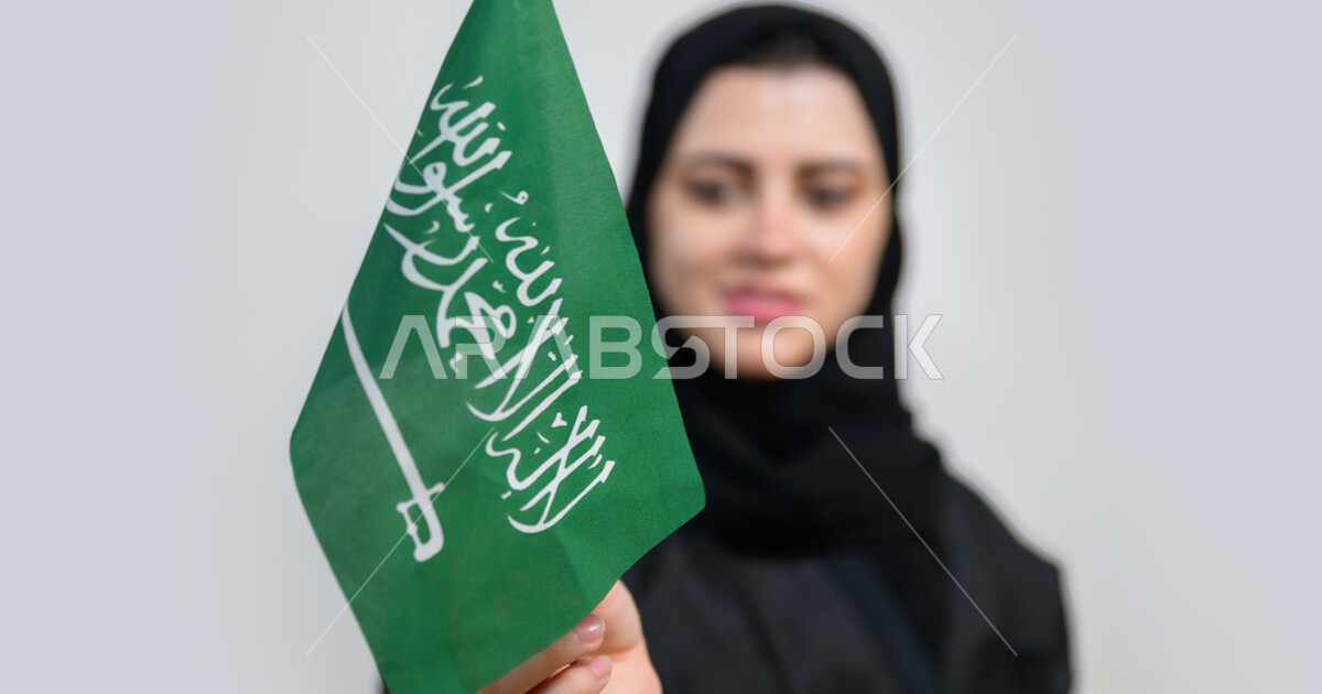Portrait of a Saudi Arabian Gulf woman holding the flag of Saudi Arabia ...