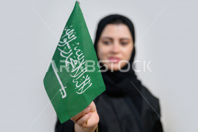 Portrait of a Saudi Arabian Gulf woman holding the flag of Saudi Arabia ...