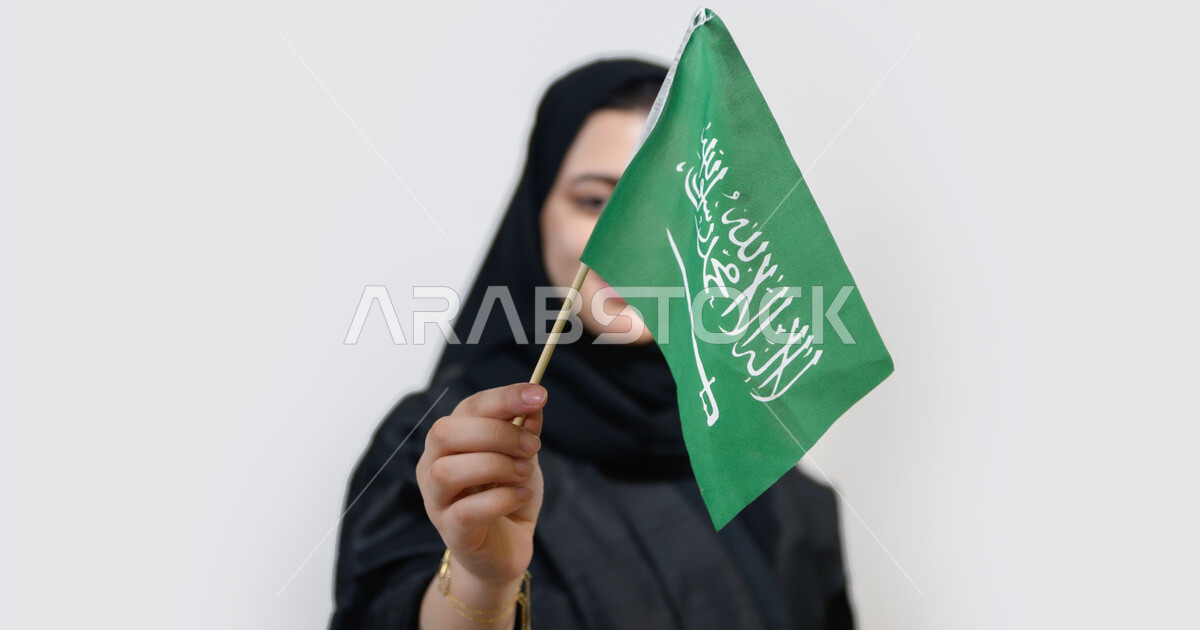 Portrait of a Saudi Arabian Gulf woman holding the flag of Saudi Arabia ...