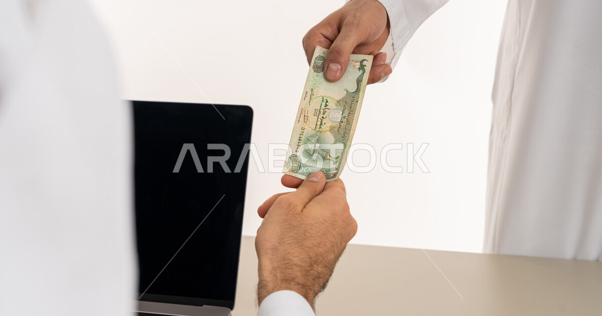Recording customer payments on laptop, currency in UAE markets ...