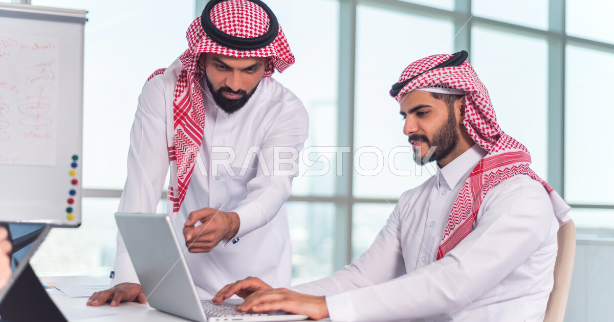 A group of Saudi Gulf businessmen meeting inside the company, using a ...