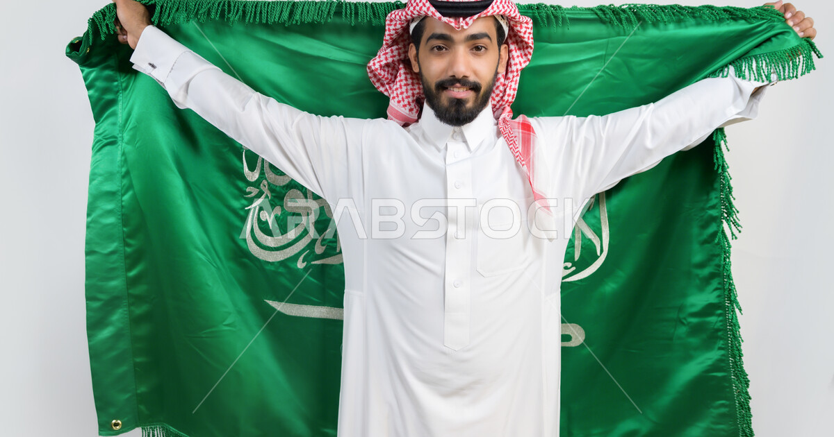 Portrait of a Saudi Arabian Gulf Arab man raising the flag of Saudi ...