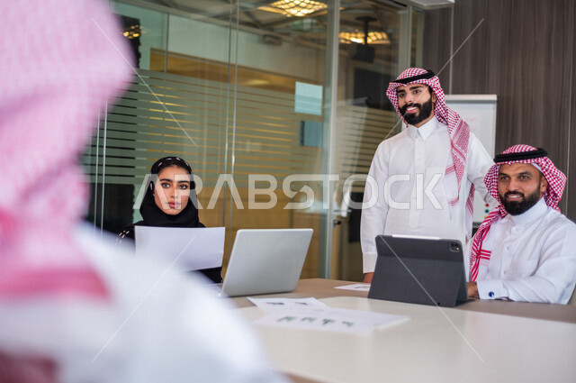 A group of businessmen and a businesswoman inside a Saudi company, a ...