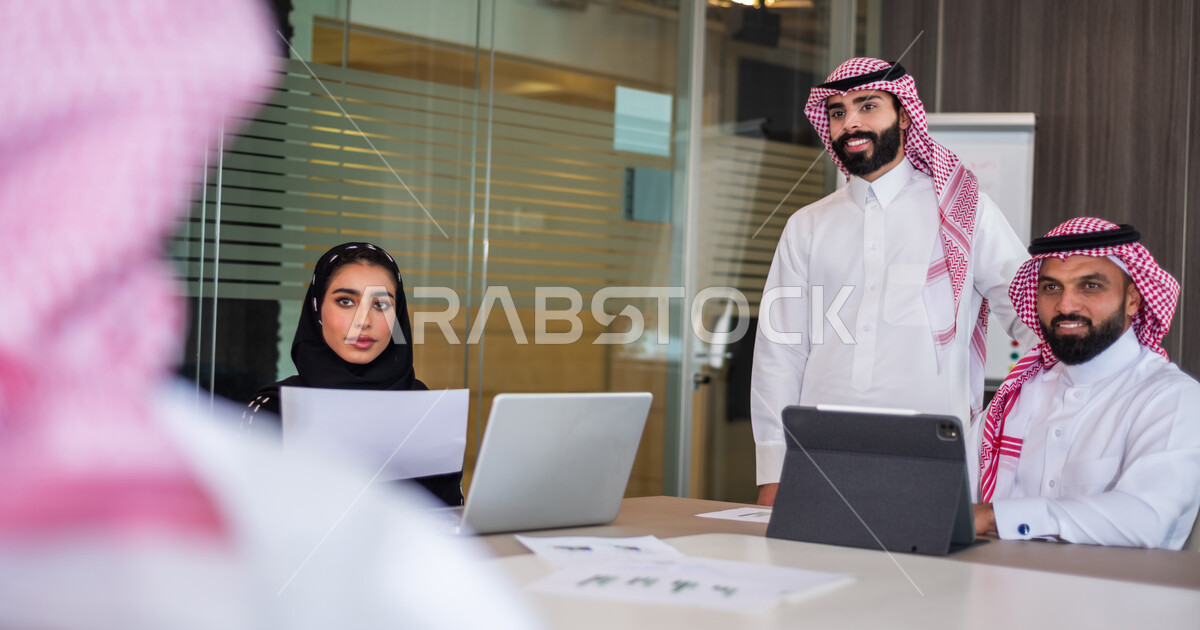 A group of businessmen and a businesswoman inside a Saudi company, a ...