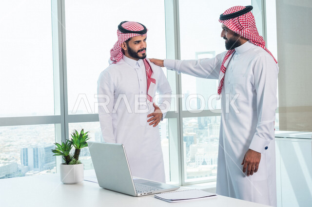 Two Saudi Arabian Gulf employees wearing traditional Gulf dress, follow ...