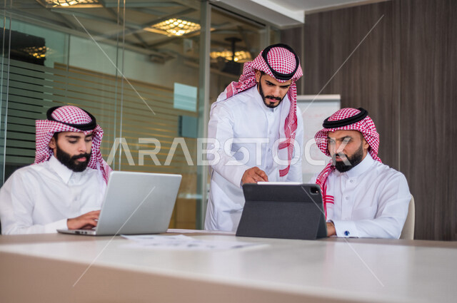 A group of Saudi Gulf businessmen meeting inside the company, using the ...