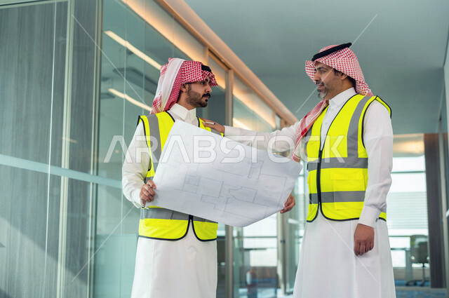 Two Saudi Gulf architects holding a blueprint for a construction ...