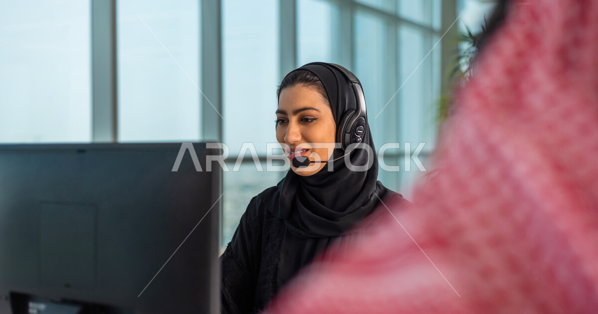 Two Saudi Arabian Gulf employees working in customer service, making a ...