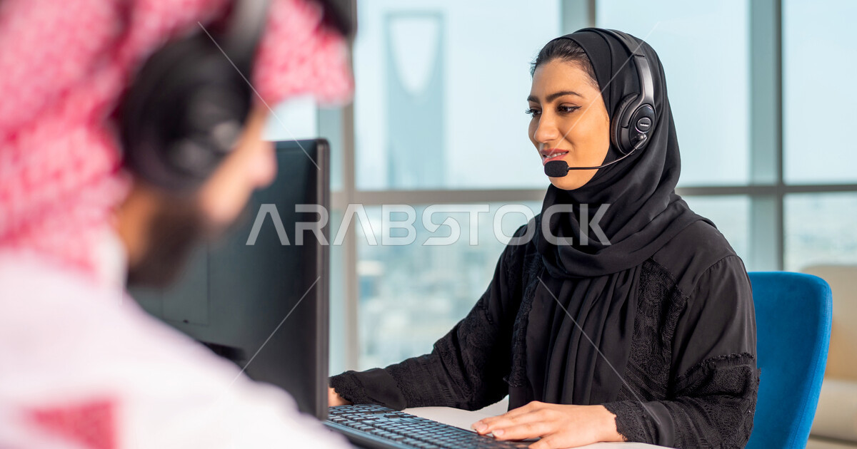 Two Saudi Arabian Gulf employees working in customer service, making a ...