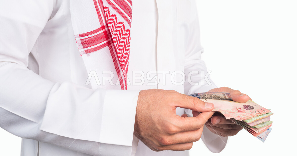 Portrait of a Saudi Arabian Gulf man holding a pile of banknotes in his ...
