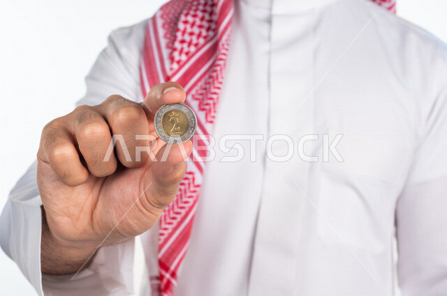 Portrait of a Saudi Arabian Gulf man holding a coin in his hand, a ...