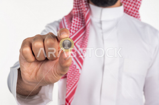 Portrait of a Saudi Arabian Gulf man holding a coin in his hand, a ...