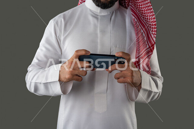Portrait of a Saudi Arabian Gulf man wearing traditional dress holding ...