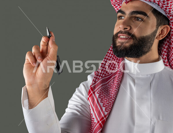 Portrait of a Saudi Arabian Gulf man wearing traditional dress holding ...