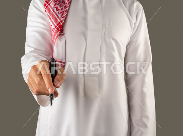 Portrait of a Saudi Arabian Gulf man wearing traditional dress holding ...