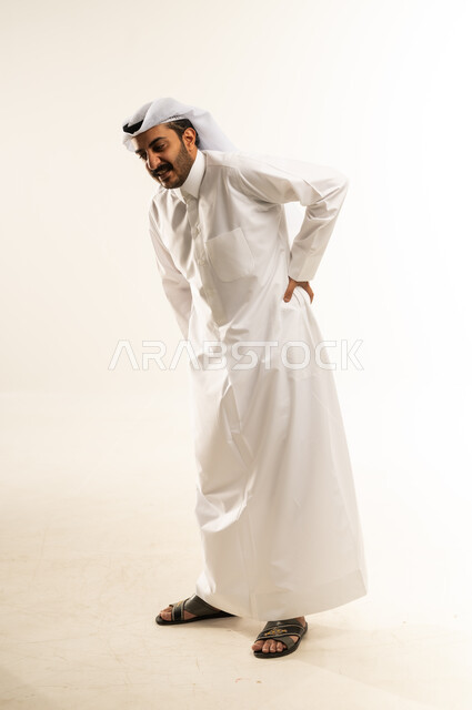 Back and spine pain, portrait of a Qatari Gulf Arab man wearing a ...
